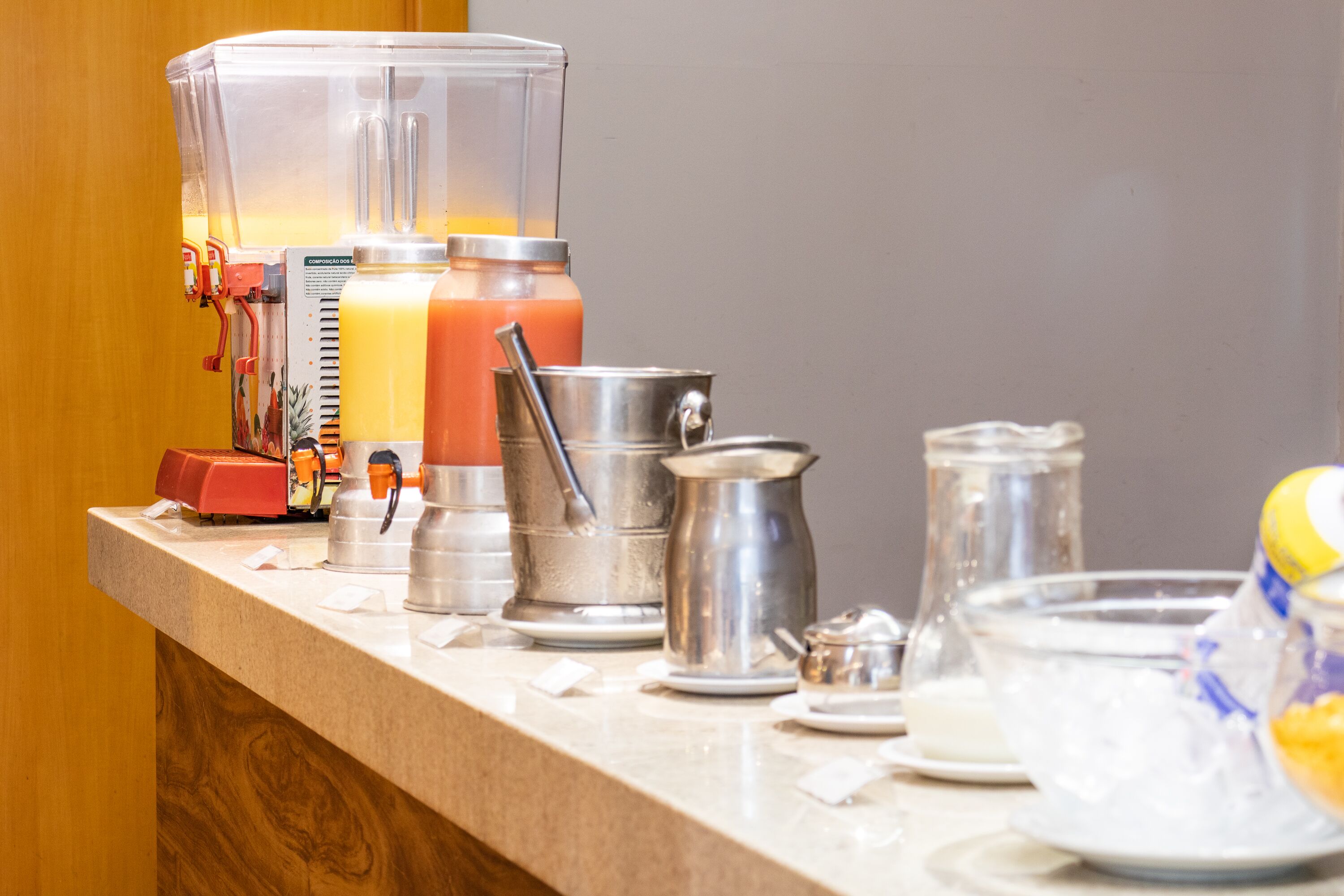 Uma mesa de pequeno-almoço com máquina de café, liquidificador e diversos utensílios de cozinha.
