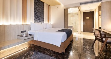 Quarto de hotel com cama, mesa de cabeceira e área de chuveiro.