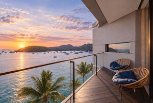 Varanda com cadeiras de vime, vista para o mar e barcos.