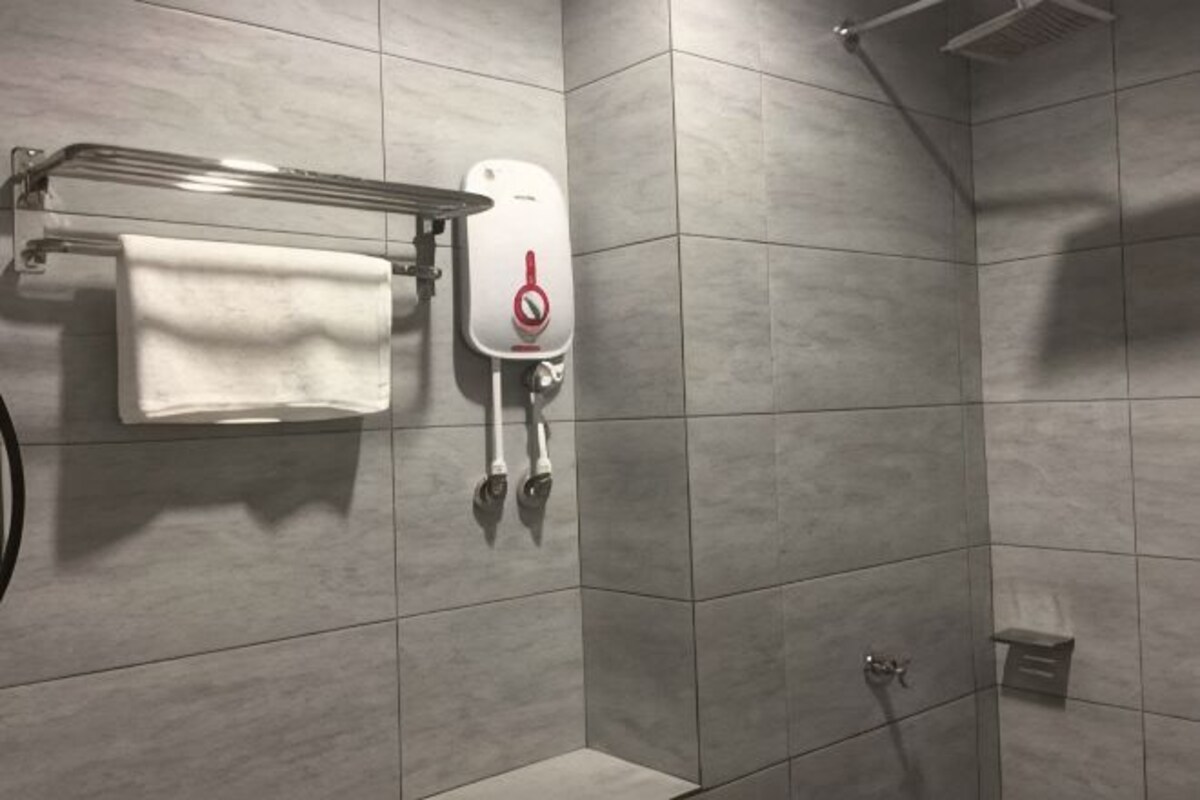 Área do chuveiro com porta-toalhas, dispensador de sabonete e chuveiro.