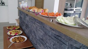 Disposição de buffet com diversos pratos, incluindo doces, legumes e um prato de fatias de maçã.