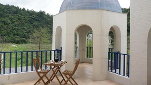 Uma varanda com mesa e cadeiras, uma estrutura em cúpula e vista para uma paisagem verde.