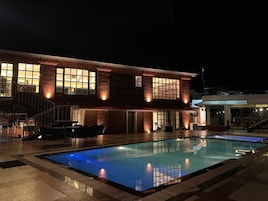 Um hotel com piscina, área de estar externa e escadaria que leva à entrada.