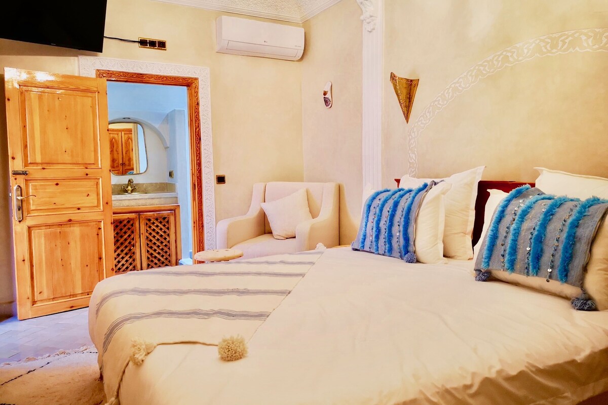 Quarto com uma cama, guarda-roupa de madeira, espelho e ar condicionado fixado na parede.