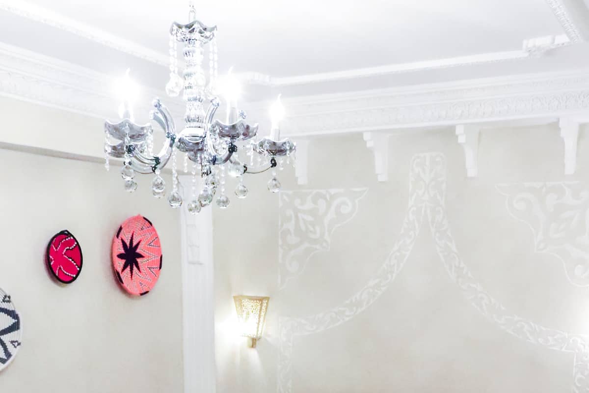 Quarto com cama, almofadas, um candelabro e decorações nas paredes.