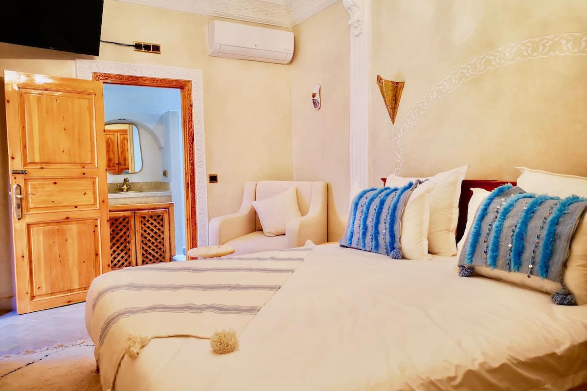 Quarto com uma cama, guarda-roupa de madeira, espelho e ar condicionado fixado na parede.