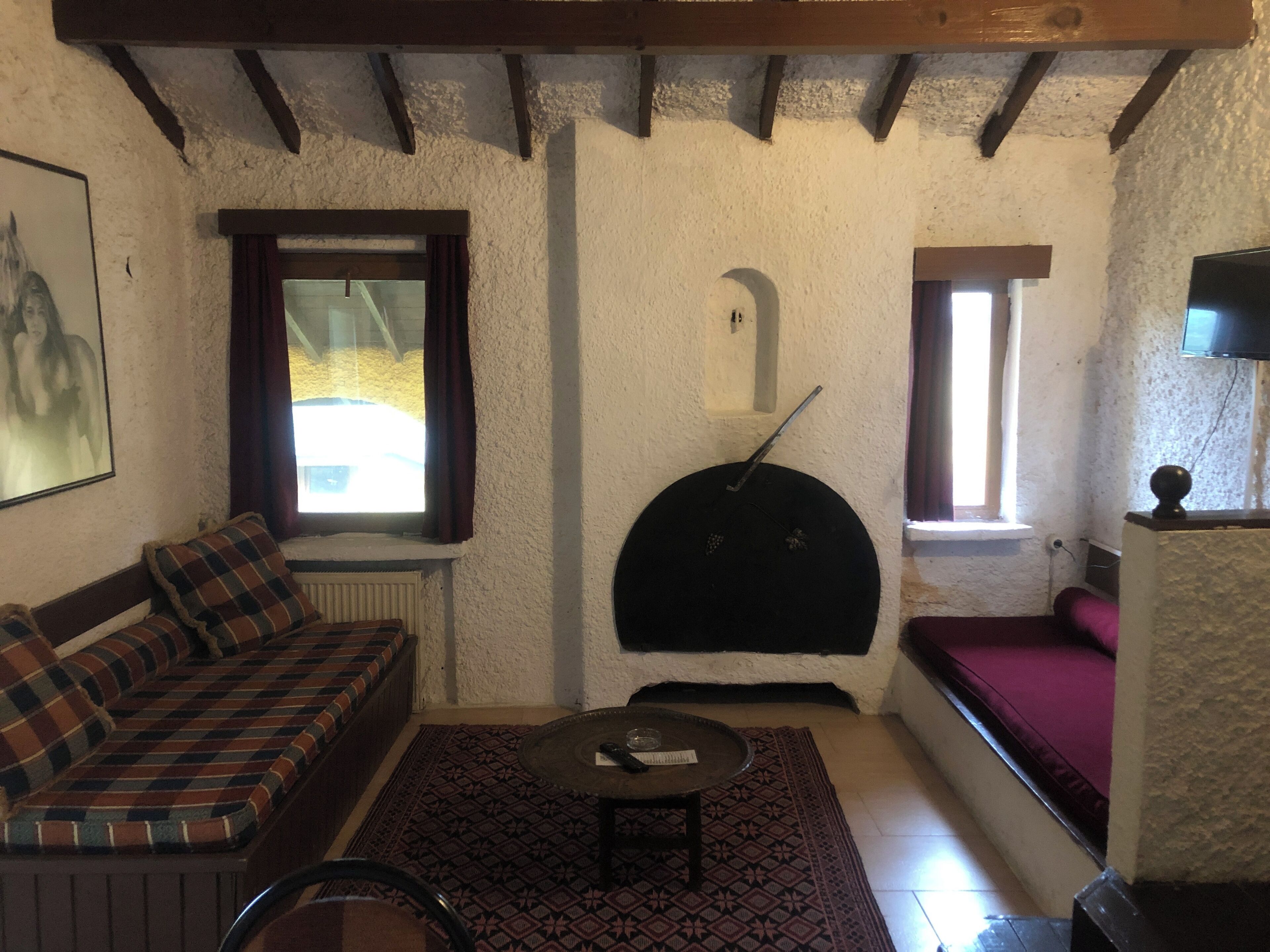 Uma sala de estar aconchegante com sofá, mesinha, lareira e janela com cortinas.
