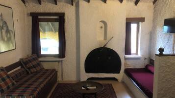 Uma sala de estar aconchegante com sofá, mesinha, lareira e janela com cortinas.