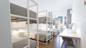 Quarto moderno com beliches, escrivaninha e cadeira.