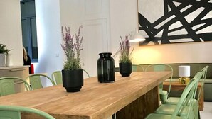 Uma sala de jantar moderna com uma mesa de madeira, cadeiras verdes e dois vasos pretos com plantas.