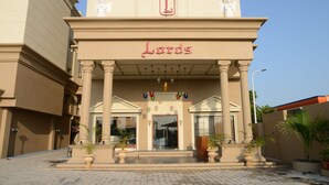Entrada de hotel com um letreiro 'Lords' em destaque, colunas e plantas em vasos.