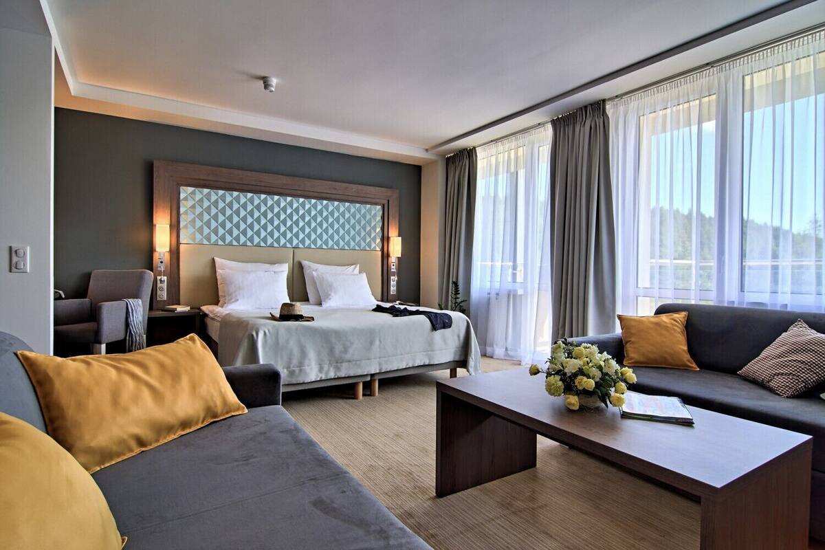 Quarto de hotel com cama, sofá, escrivaninha e cadeira.