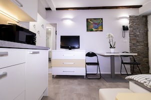 Uma cozinha moderna com micro-ondas, televisão e uma parede de destaque em pedra.
