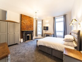 Quarto com lareira, cama, televisão e escrivaninha.