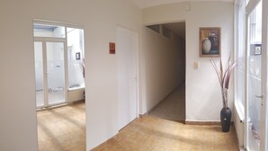 Um corredor com chão de azulejos, uma porta e um quadro na parede.
