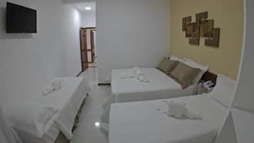 Quarto de hotel com duas camas, uma televisão fixada na parede e uma porta que dá para outro quarto.