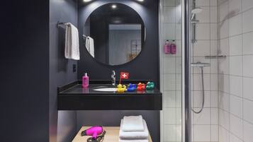 Casa de banho moderna com lavatório preto, espelho redondo, lavatório branco e chuveiro.