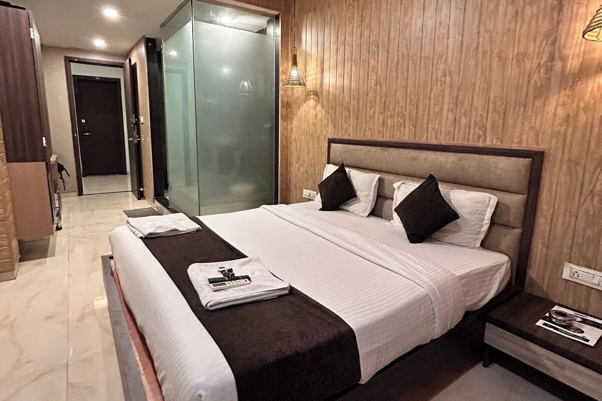 Quarto de hotel moderno com uma cama grande, uma mesa de cabeceira, um espelho e um guarda-roupa.