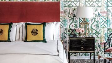 Quarto com cama, mesa de cabeceira, cadeira e papel de parede estampado.
