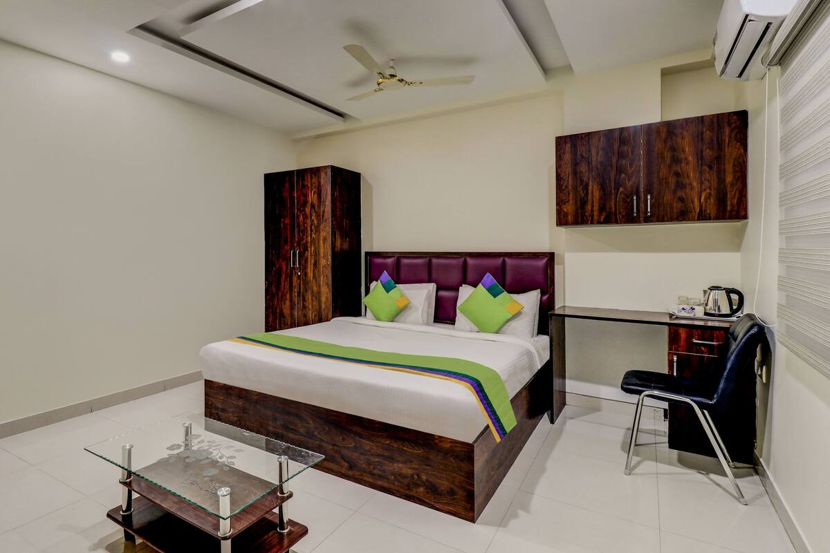 Quarto de hotel moderno com uma cama grande, uma escrivaninha e uma cadeira.