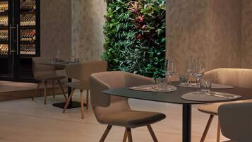 Uma área de refeições moderna com uma mesa comprida, várias cadeiras e uma parede de jardim vertical.