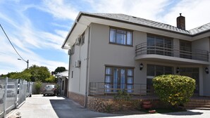 Um edifício residencial de dois andares com varanda, garagem e um jardim bem cuidado.