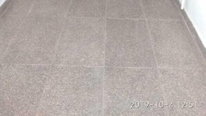 Um corredor com piso cerâmico e escada que leva a um andar superior.
