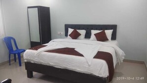 Quarto com cama, guarda-roupa e uma cadeira azul.