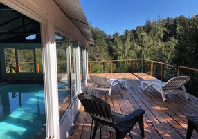 Um deck de madeira com cadeiras de lounge e piscina.