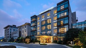 Hotel de vários andares com design moderno, destacando uma entrada imponente com toldo e sinalização iluminada.