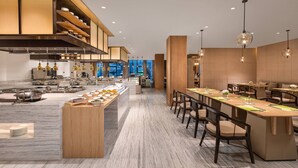 Restaurante moderno com um balcão extenso, várias áreas de estar e vista para o horizonte urbano através de grandes janelas.