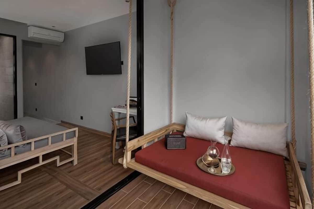 Um quarto com uma cama, uma escrivaninha, uma cadeira e uma televisão na parede.