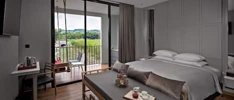 Quarto moderno com cama grande, escrivaninha e varanda com vista para o verde.