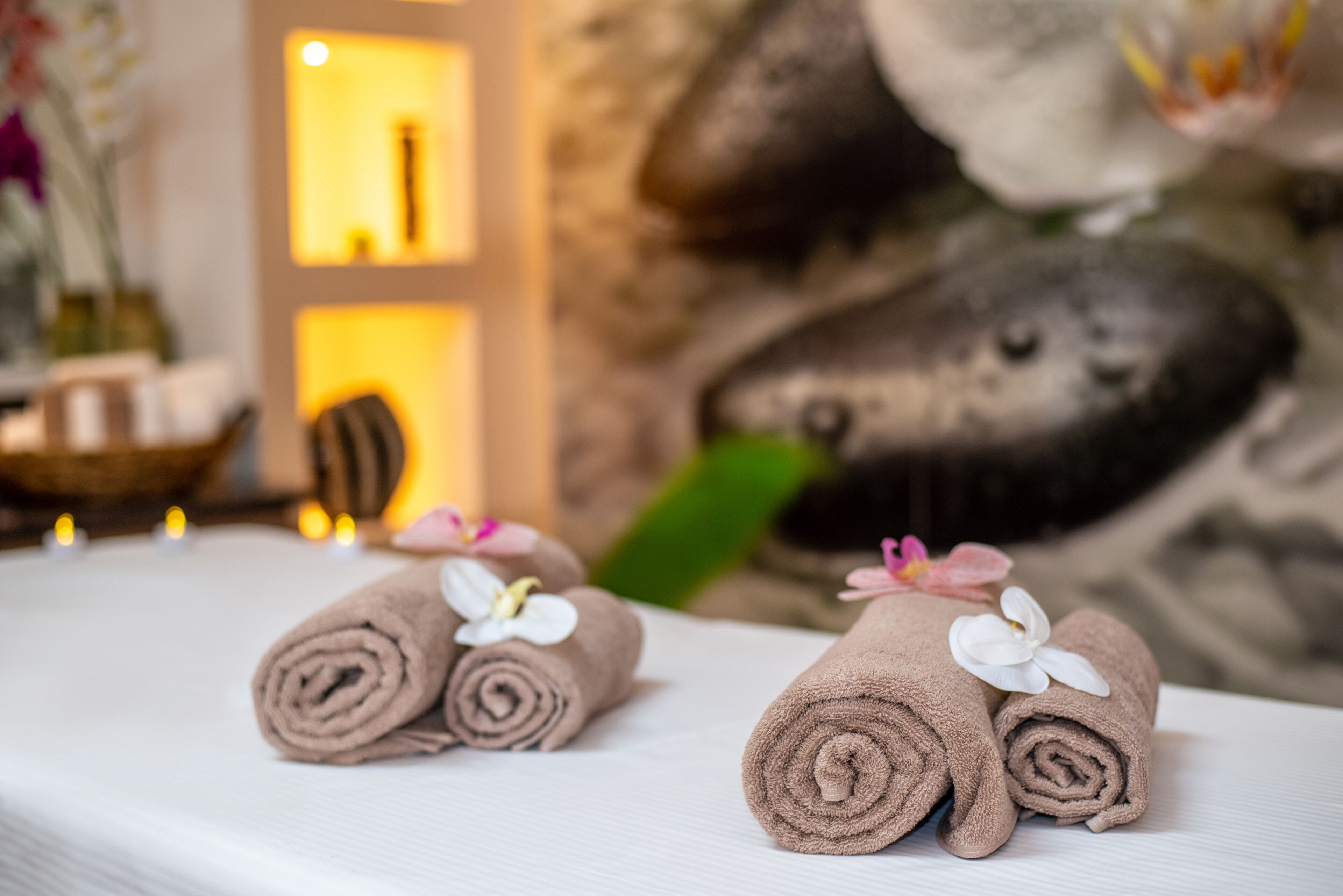 Toalhas bem organizadas com flores brancas, um mural decorativo de peixes e uma iluminação ambiente acolhedora ao fundo.