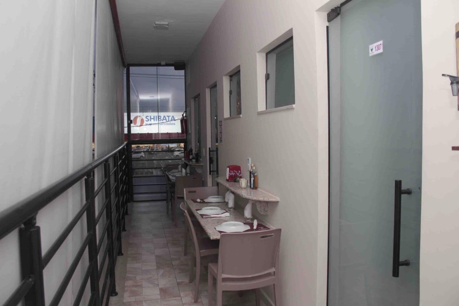 Um corredor estreito com área de jantar, incluindo mesa, cadeiras, geladeira e janela com vista para um estacionamento.