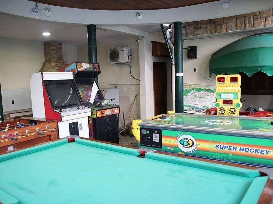 Uma área de lazer com mesa de pebolim, mesa de pingue-pongue e mesa de bilhar.