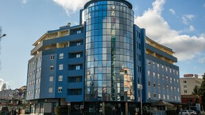 Um hotel moderno com fachada de vidro curva, vários andares e um destaque para o letreiro 'Generali'.