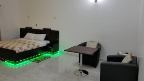 Quarto com cama, uma mesinha e uma cadeira.