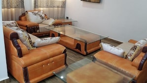 Sala de estar com sofás de couro, mesa de centro de vidro e almofadas estampadas.