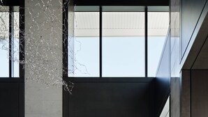 Um espaço de escritório moderno com grandes janelas, teto alto e vista para o horizonte da cidade.
