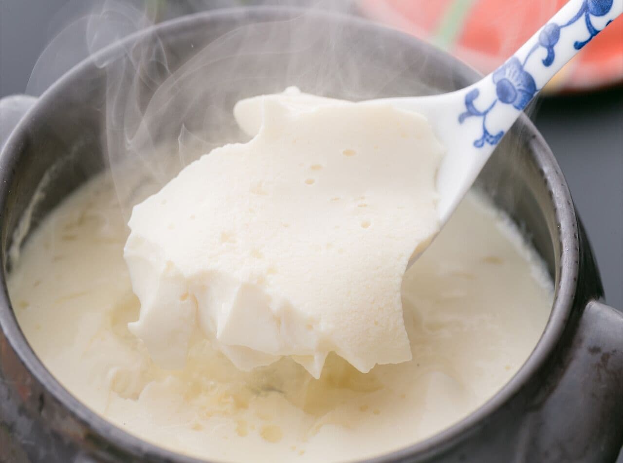 Uma colherada de um alimento cremoso e branco sendo retirada de uma panela.