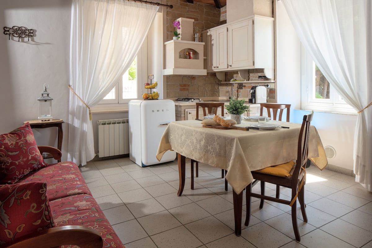 Cozinha acolhedora com mesa de jantar, cadeiras e um sofá vermelho.