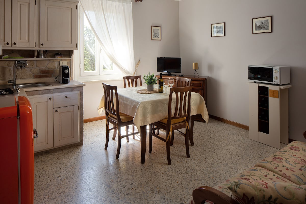 Uma cozinha compacta com área de refeições, televisão e micro-ondas.