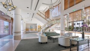 Um hall amplo com escada, área de estar e grandes janelas.