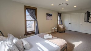 Quarto de hotel com cama, cadeira, mesinha e guarda-roupa.