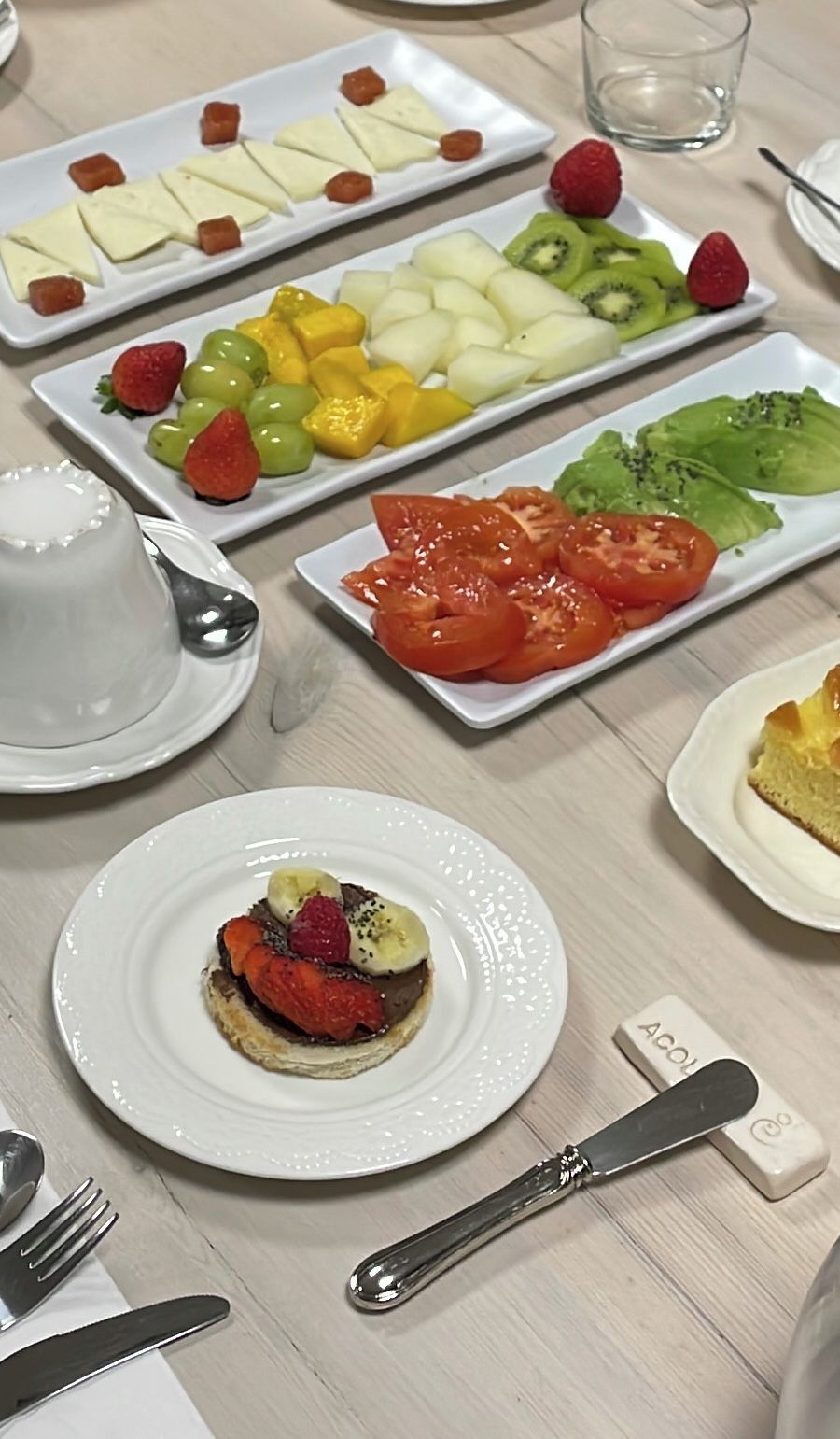 Uma mesa com vários tabuleiros de fruta e uma sobremesa numa placa.
