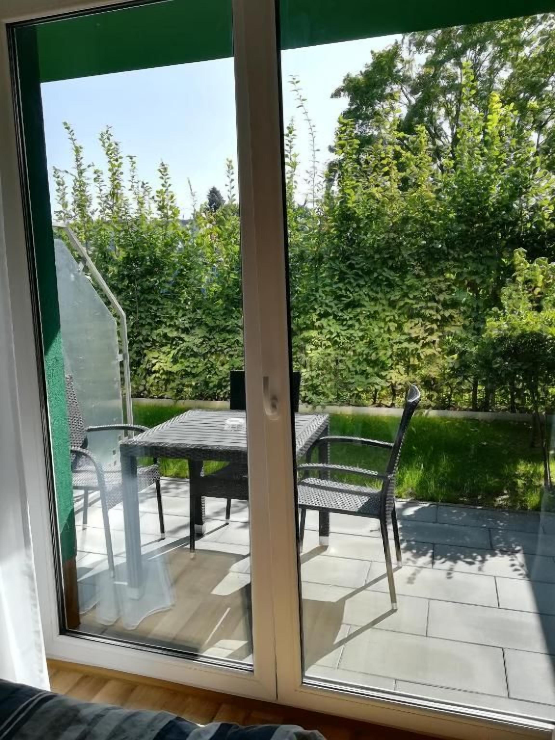 Porta de correr de vidro que dá para um pátio externo com mesa e cadeiras.