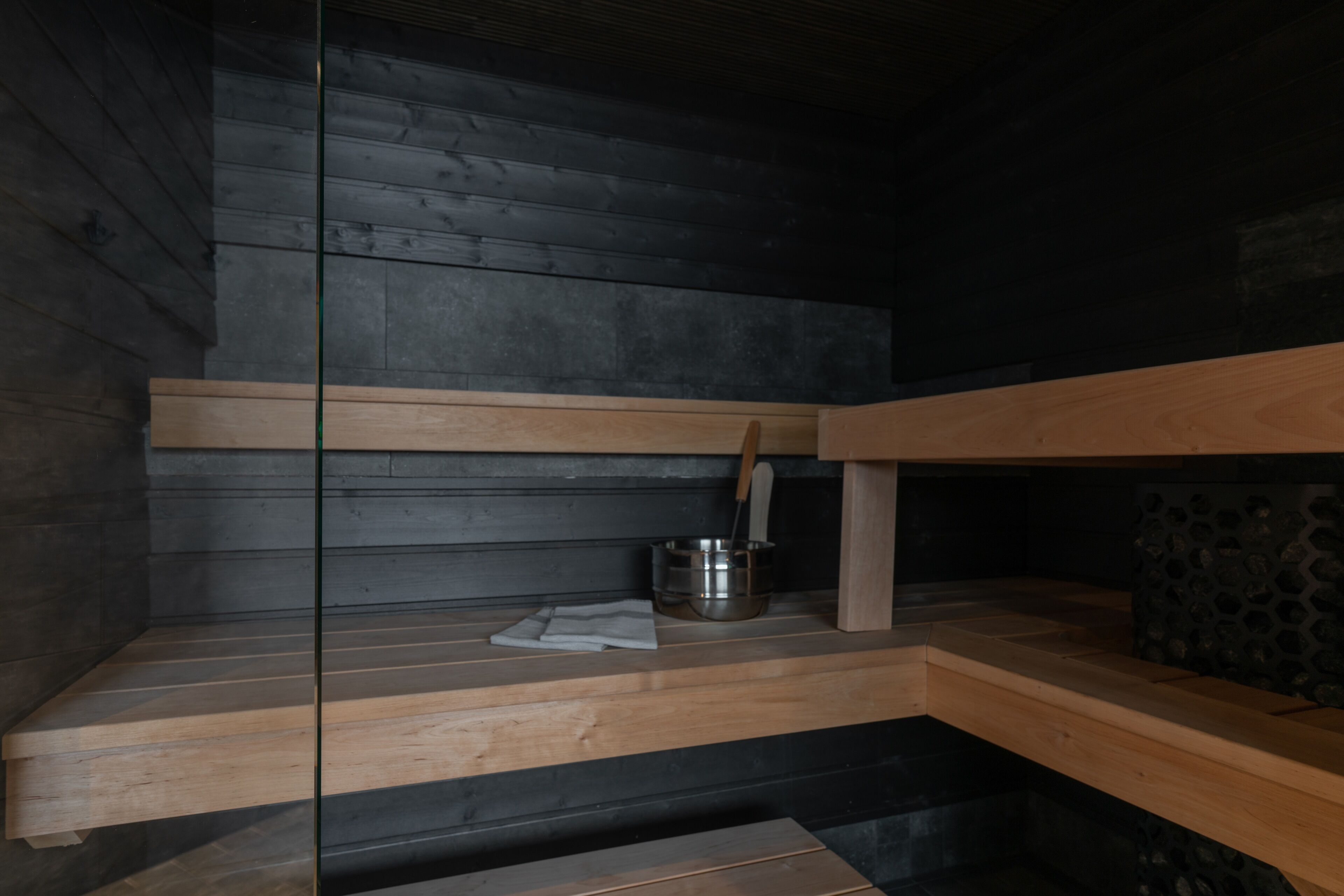 Uma sauna com bancos de madeira e um recipiente de metal.