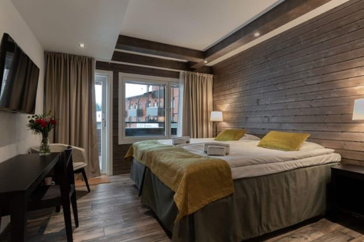 Quarto de hotel com uma cama, mesa de cabeceira e vista para edifícios.
