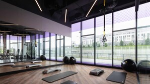 Uma academia moderna com equipamentos de ginástica, janelas amplas e vista para a cidade.